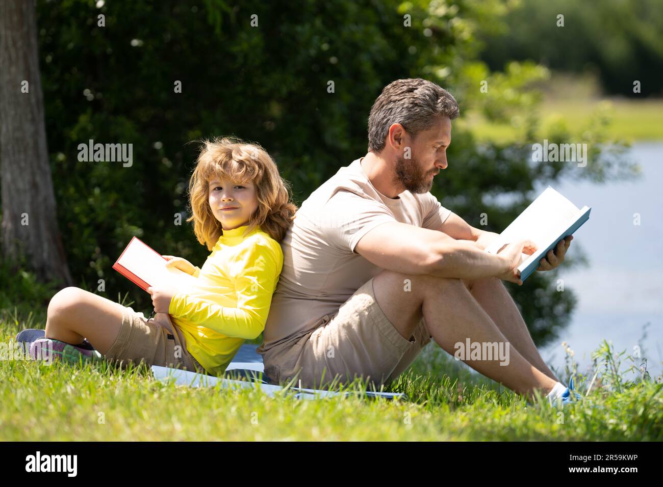 Lovely family reading a book on grass. Boy and dad having a picnic in ...
