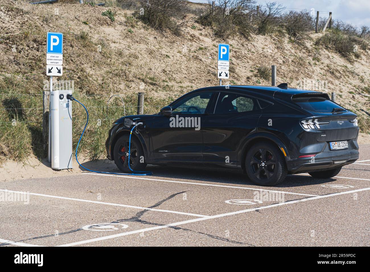 Charging modern black electric car from station outdoors in the ...