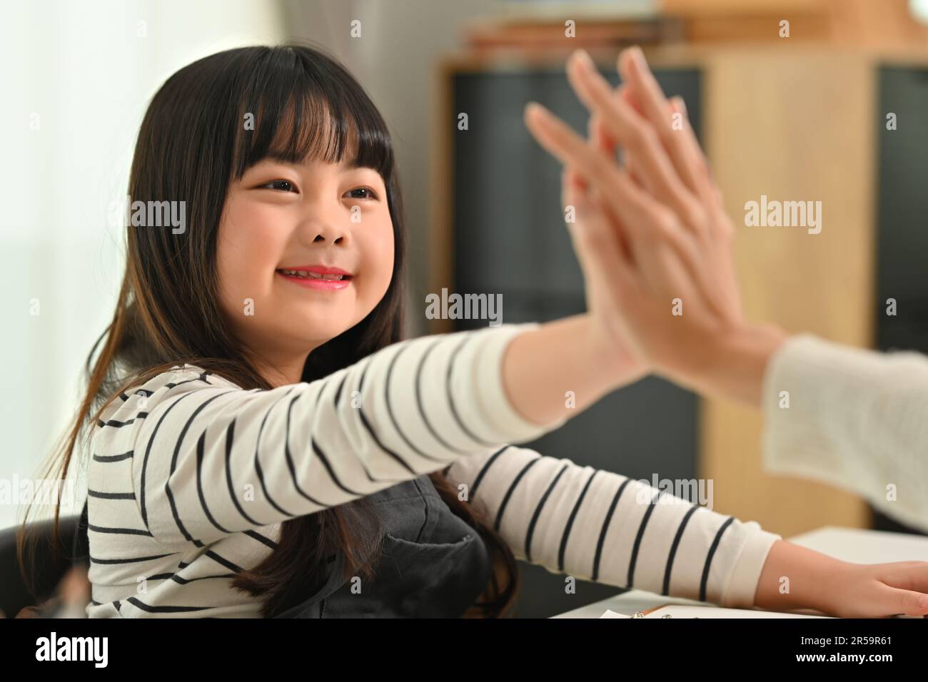 Cute little girl finish schoolwork giving high five to mother. Distance ...