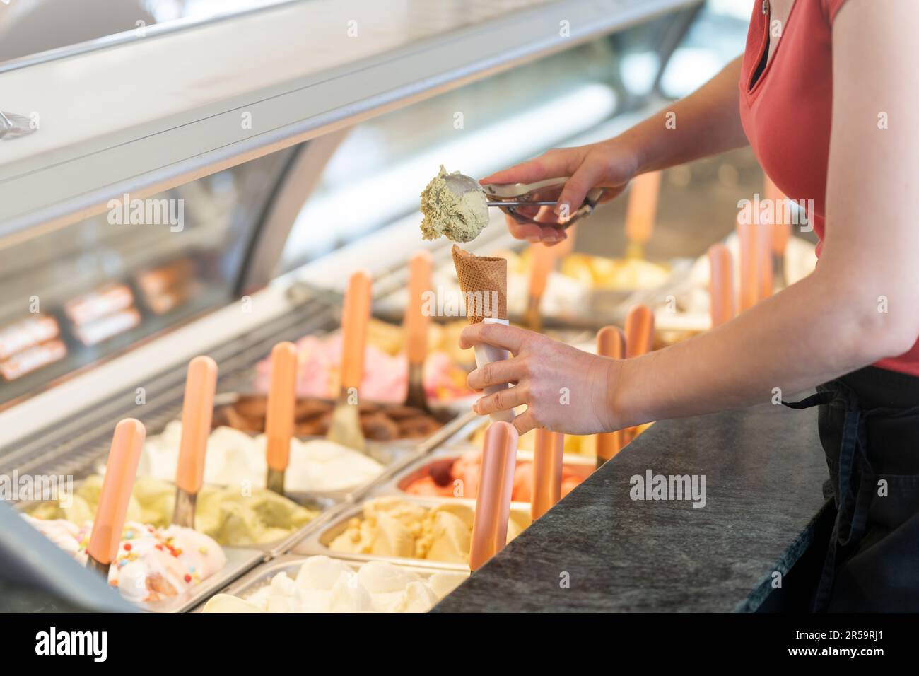 Ice cream showcase with a saleswoman preparing an ice cream cone Stock ...