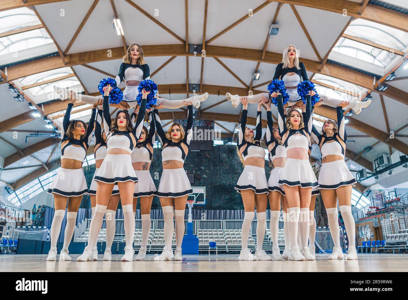 Cheerleader doing a split while other girls holidng her up in the air ...