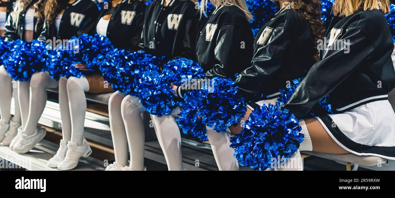 Closeup legs of cheerleader female team sitting on the bench inside a ...