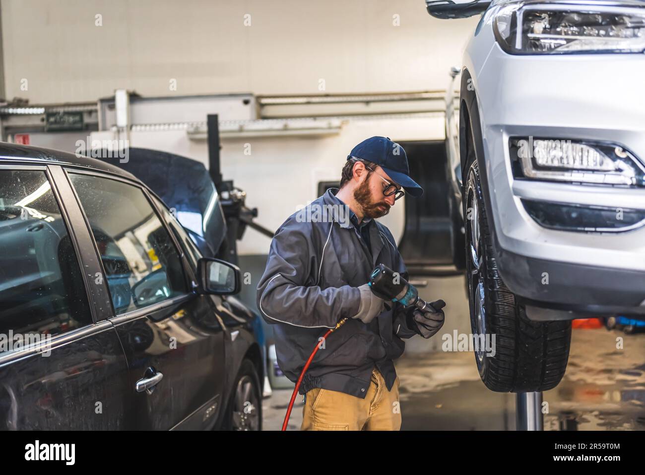 Car mechanic at work. Changing car wheel of lifted vehicle with ...