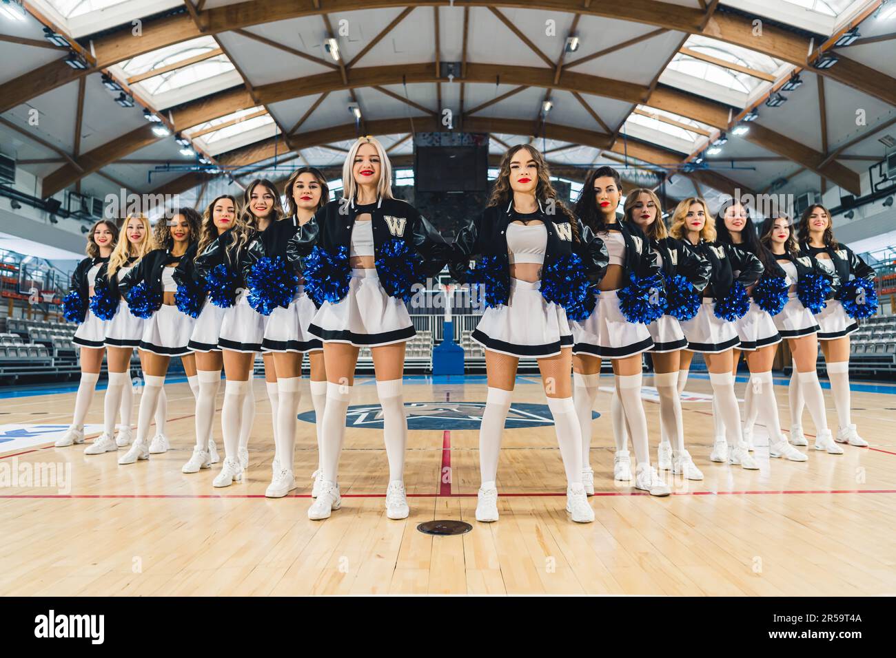 Confident cheerleader girls in mini-skirts on a basketball court. High ...