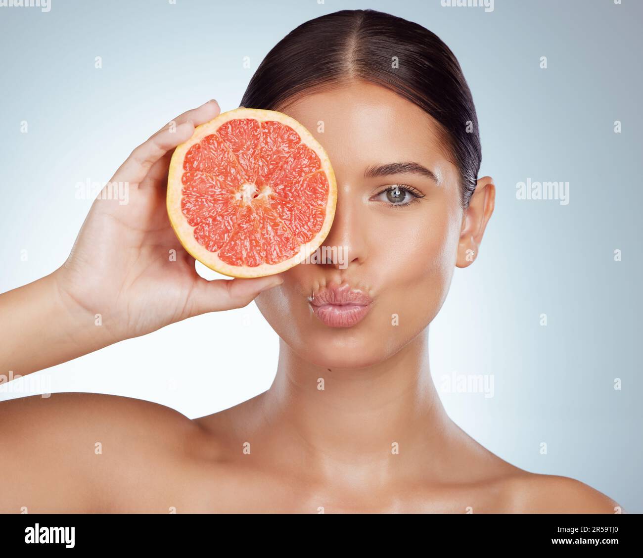 Face kiss, skincare and woman with grapefruit in studio isolated on white background. Portrait ...