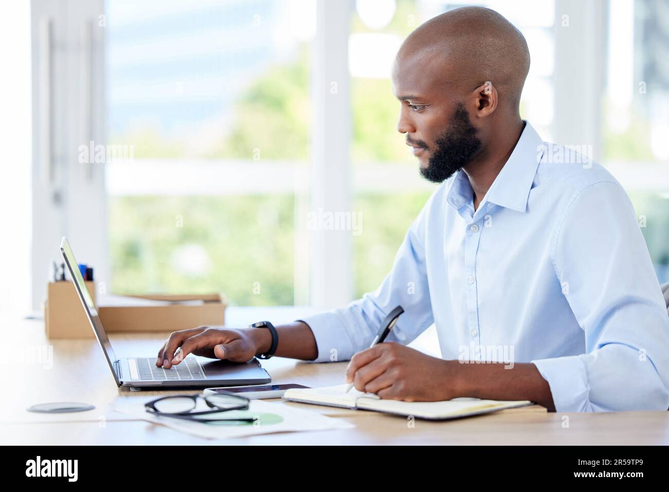 Laptop, accountant and black man writing notes for research, planning ...