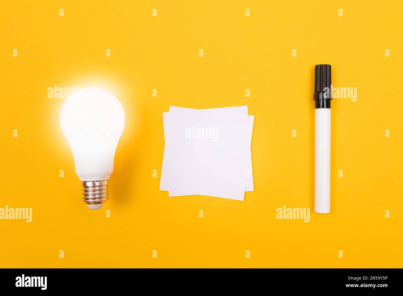 Glowing Power Saving Lamp with White Note Paper Lying on Yellow Table ...