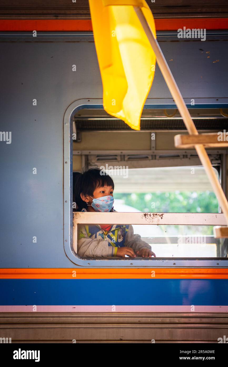 A Thai boy wearing a covid mask sits on a traditional Thai train at Hua ...