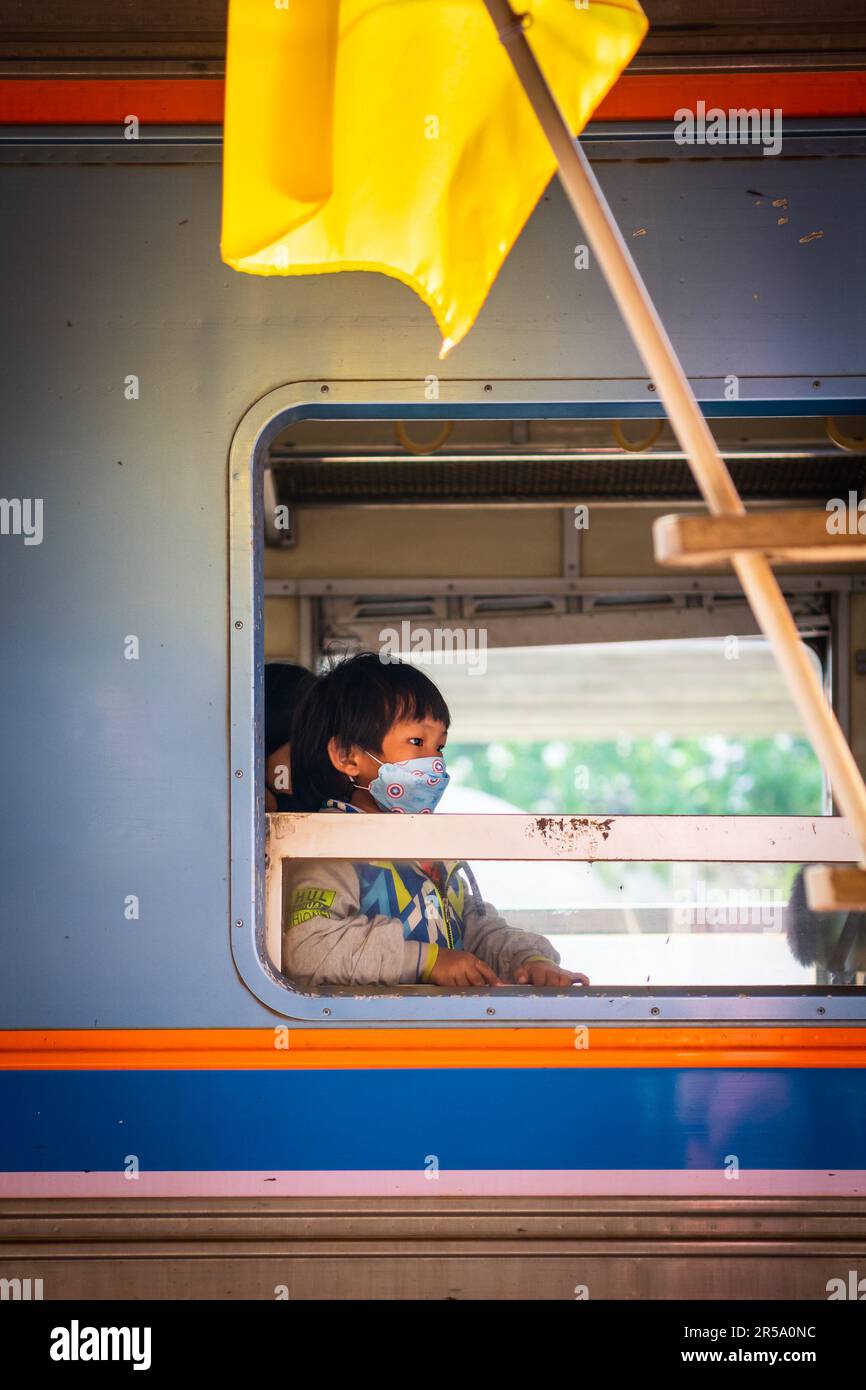 A Thai boy wearing a covid mask sits on a traditional Thai train at Hua ...