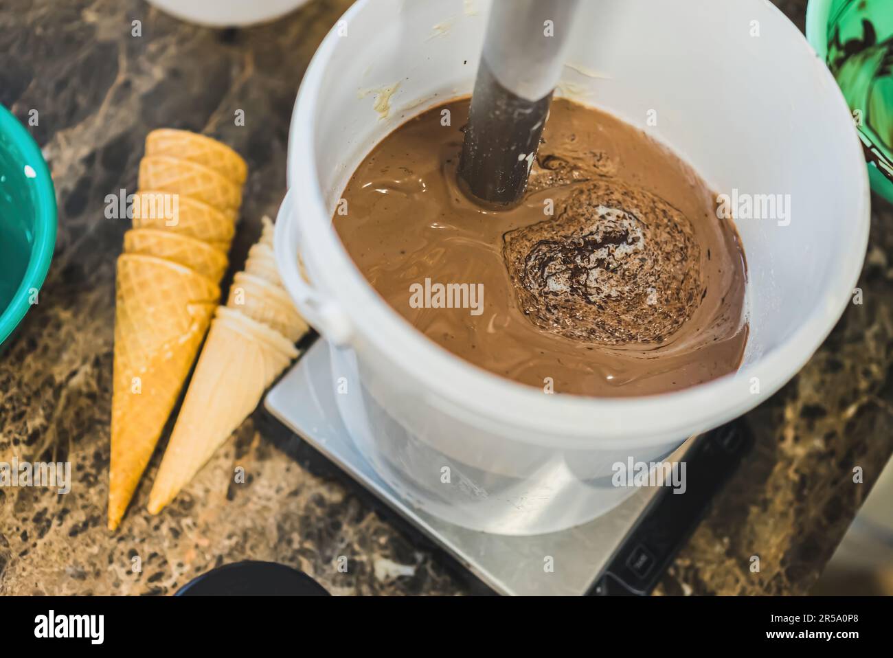 Chef mixes nuts with ice cream using big blender in a bucket preparing ...
