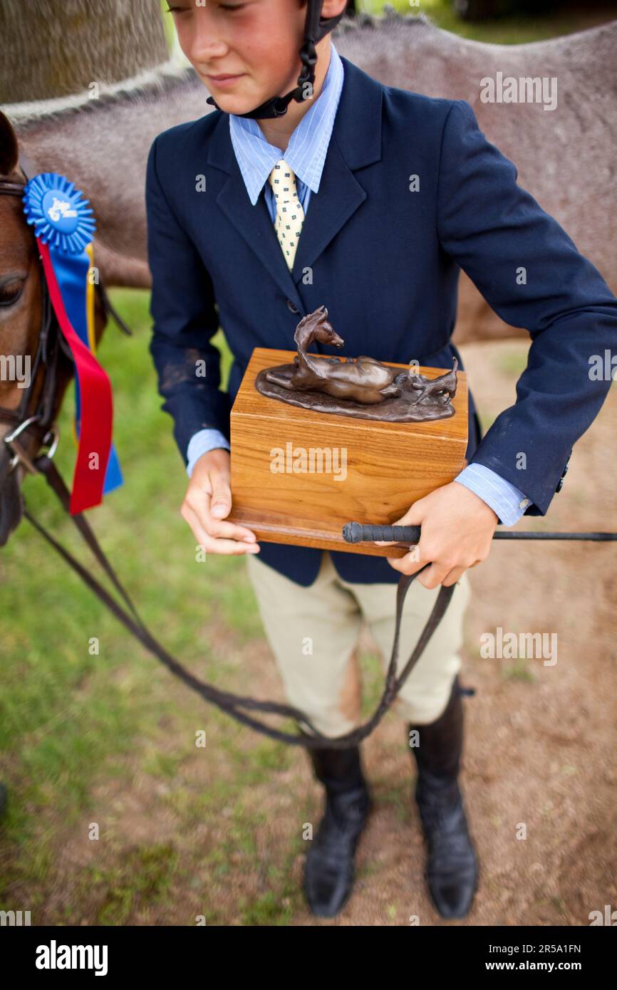 A young champion equestrian holds his prize with his pony at the Alpine ...