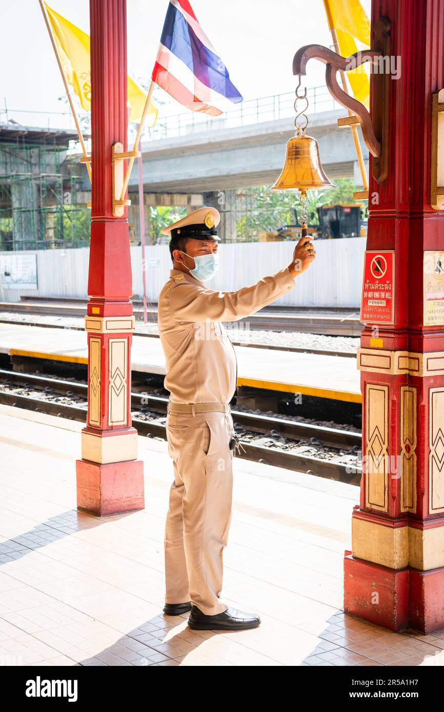 A Thai train guard rings the bell on the platform of Hua Hin train ...