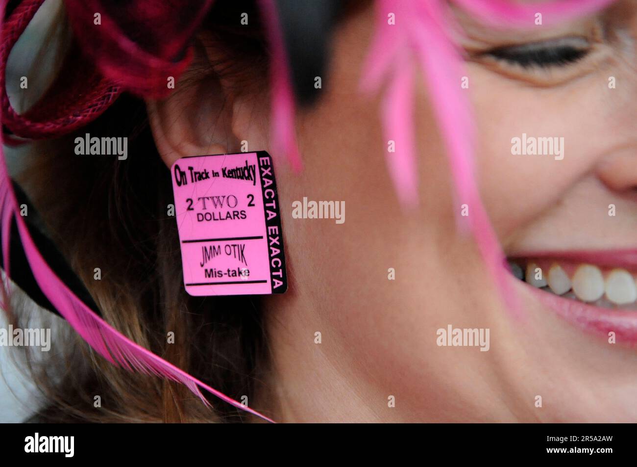 A horse race spectator wears pink commemorative ticket stub earrings to ...