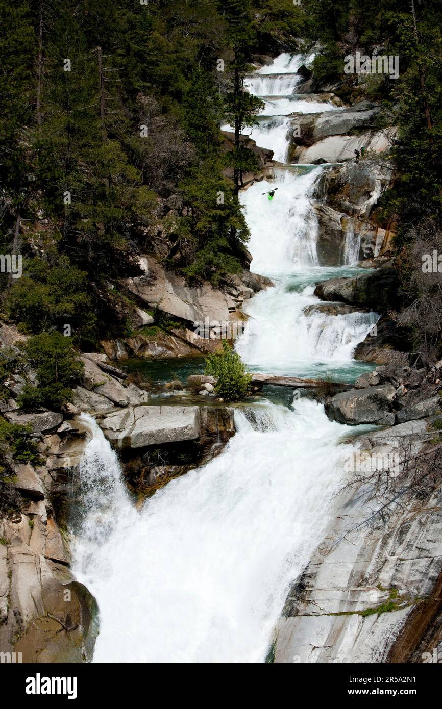 One male kayaker running a big waterfall in the middle of many other ...