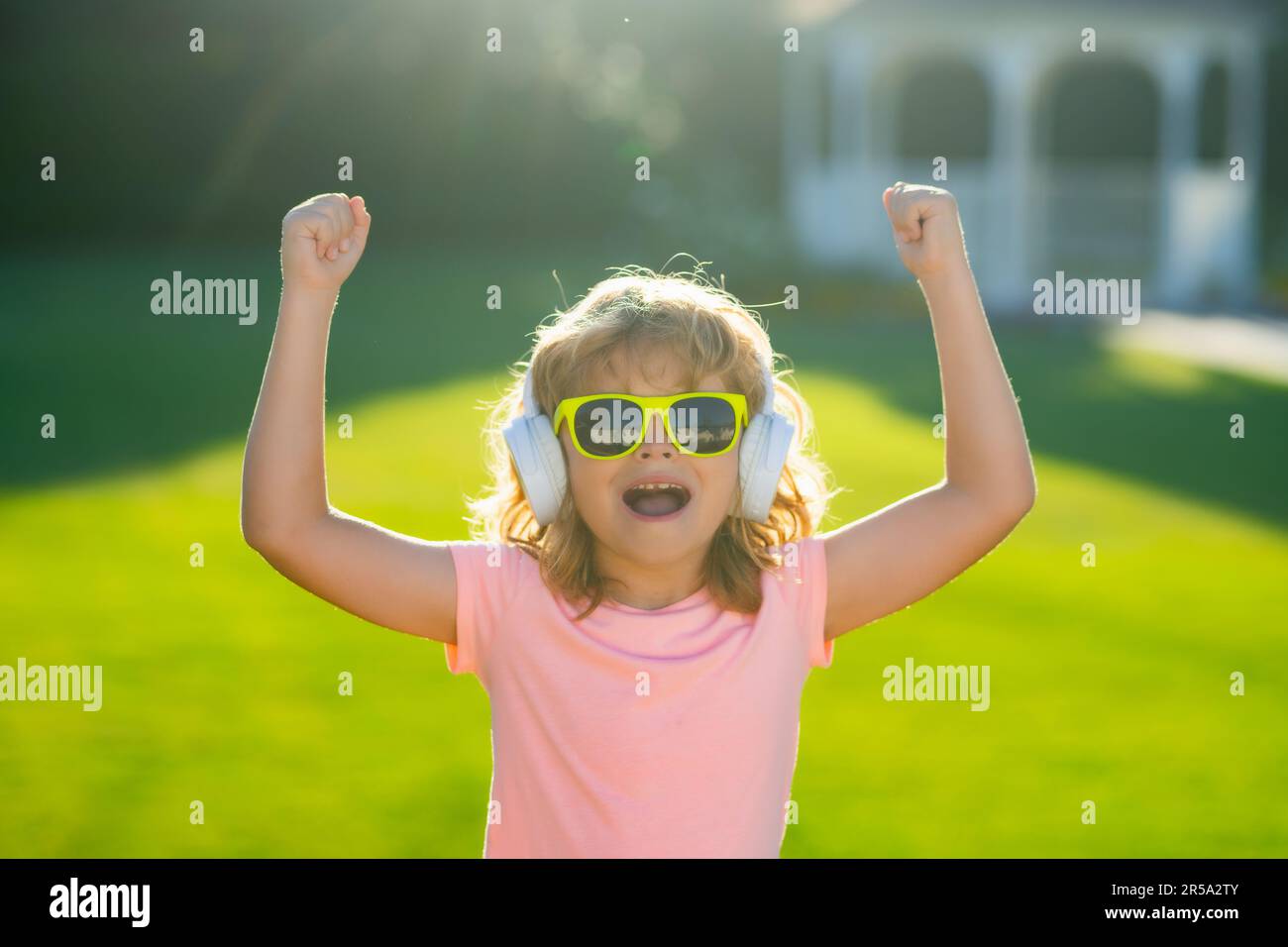 Screaming excited kid in headphones listening to music in backyard ...