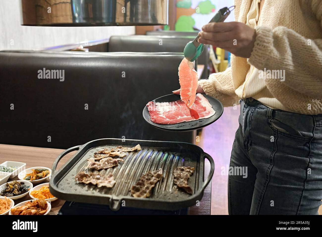 A woman hands putting meat into the skillet on the stove in the Stock ...