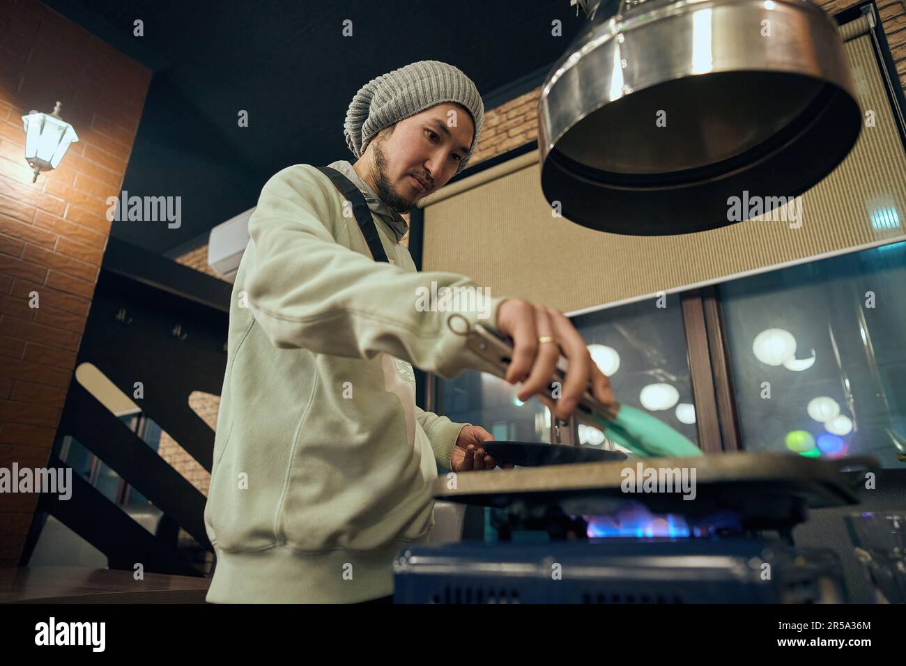 Asian woman cooks meat into the skillet on the stove in the reas Stock ...