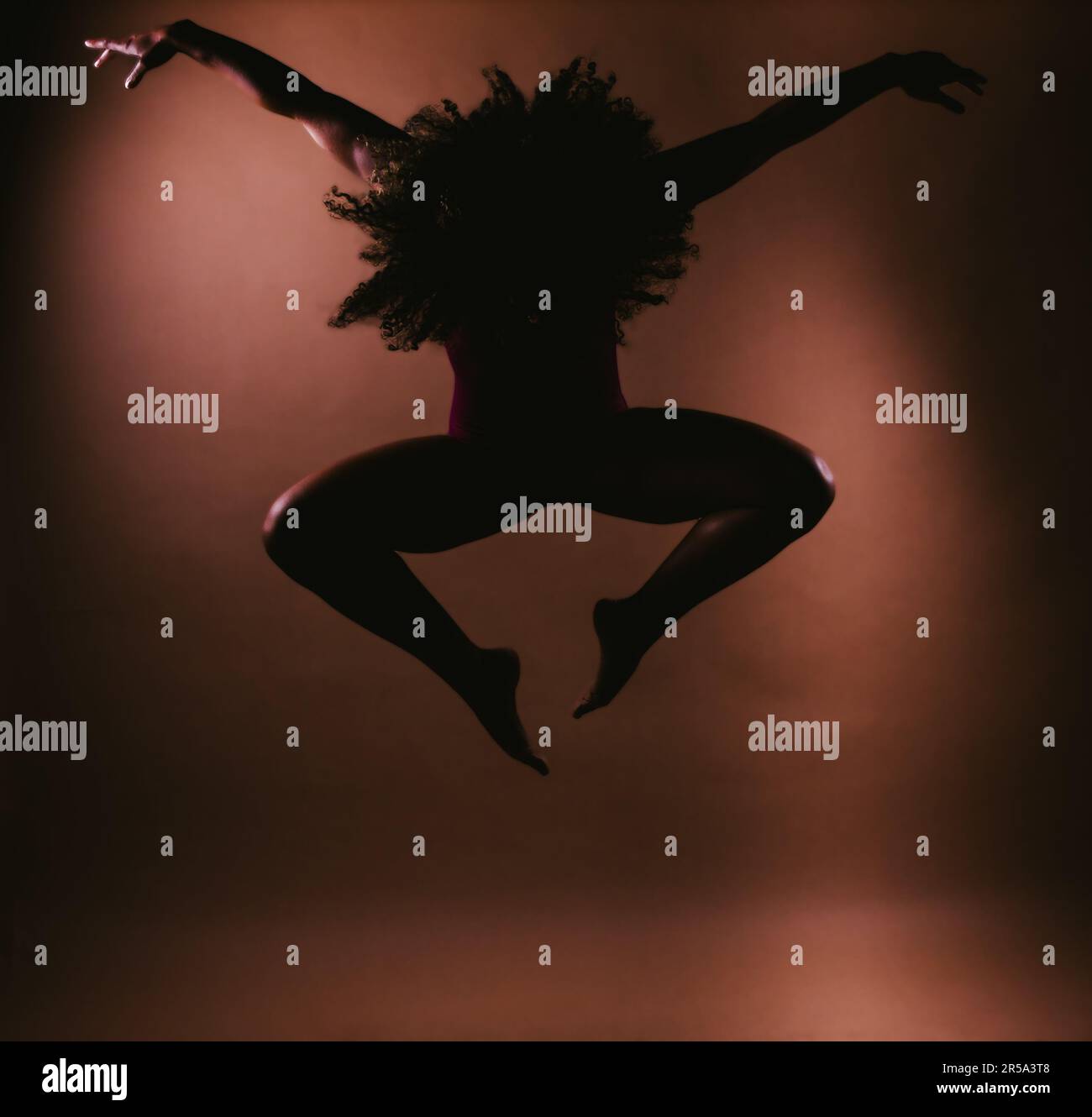 Female curly hair dancer in jump dance pose silhouette in studio Stock ...