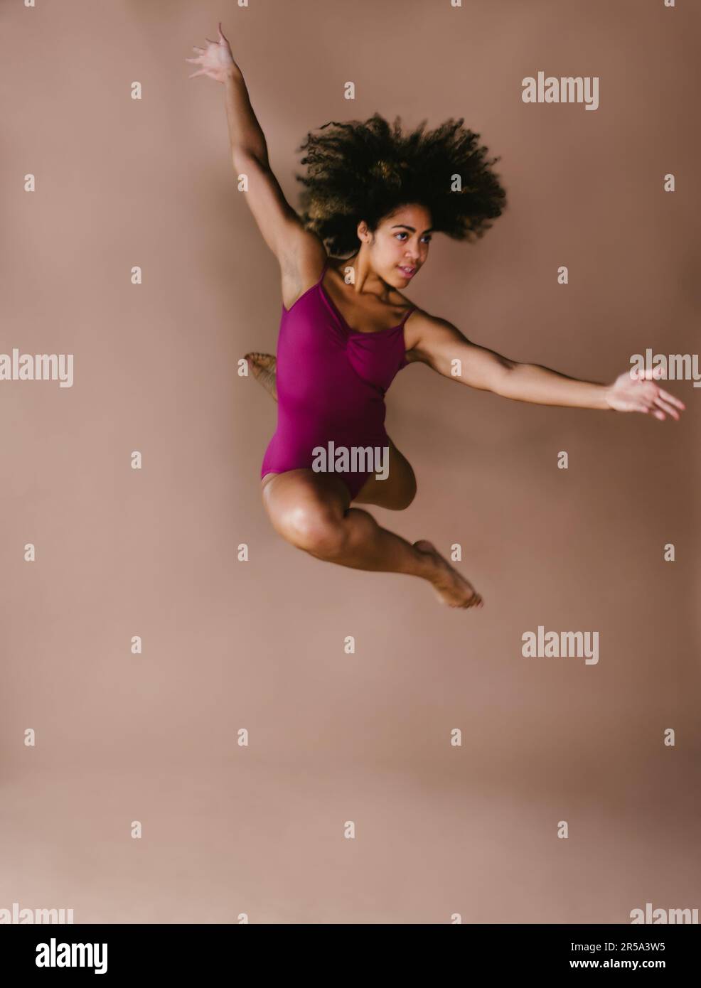 Female dancer with curly hair in leap jump dance pose Stock Photo - Alamy