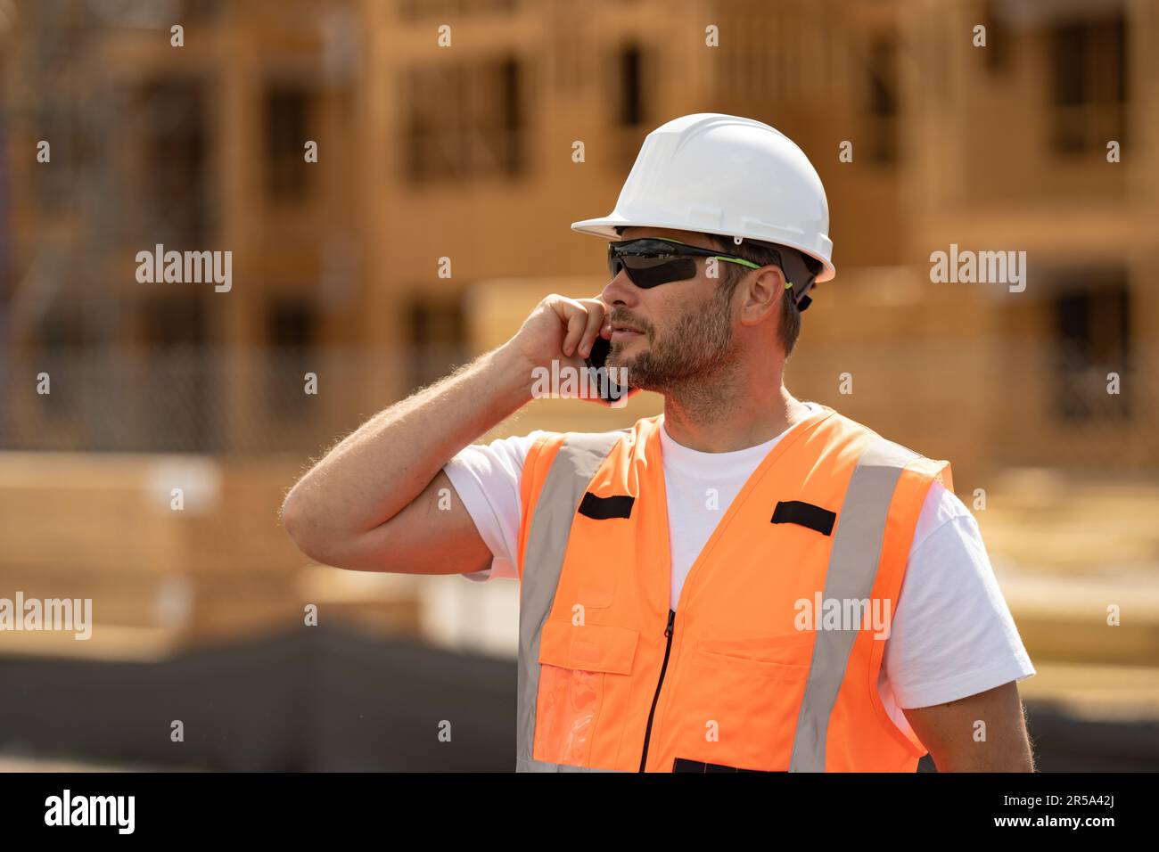 Worker call with phone in building uniform on buildings construction ...