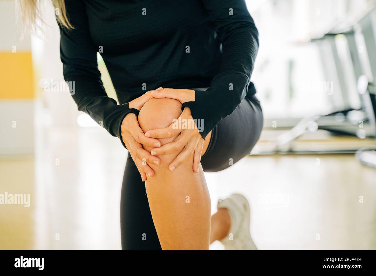 Close up woman holding knee with hands in pain after suffering injury ...