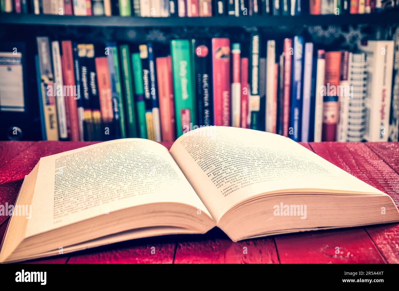 Open book with books on a shelf in the background. Shallow depth of ...