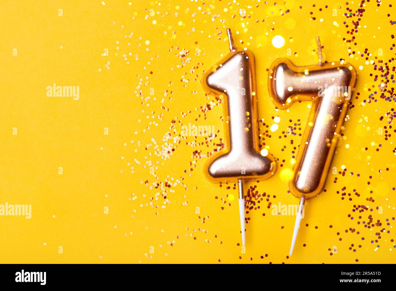 Gold candles in the form of number seventeen on yellow background with ...