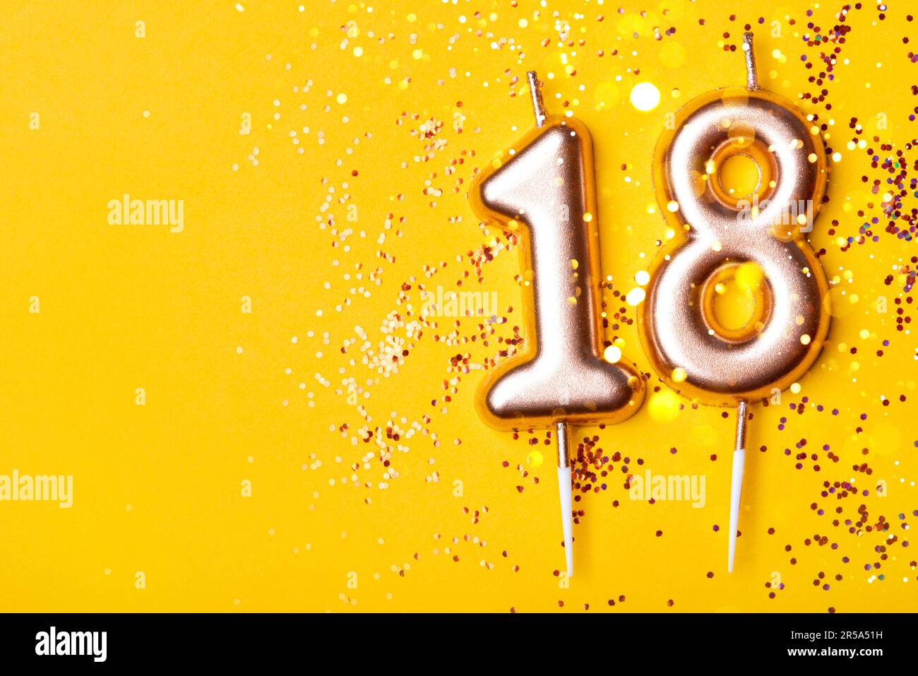 Gold candles in the form of number eighteen on yellow background with ...