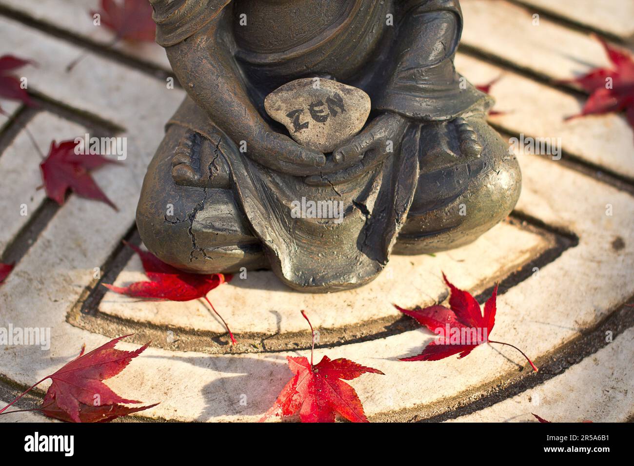 buddha sitting on the symbol of life, in the hands a stone letterling ...