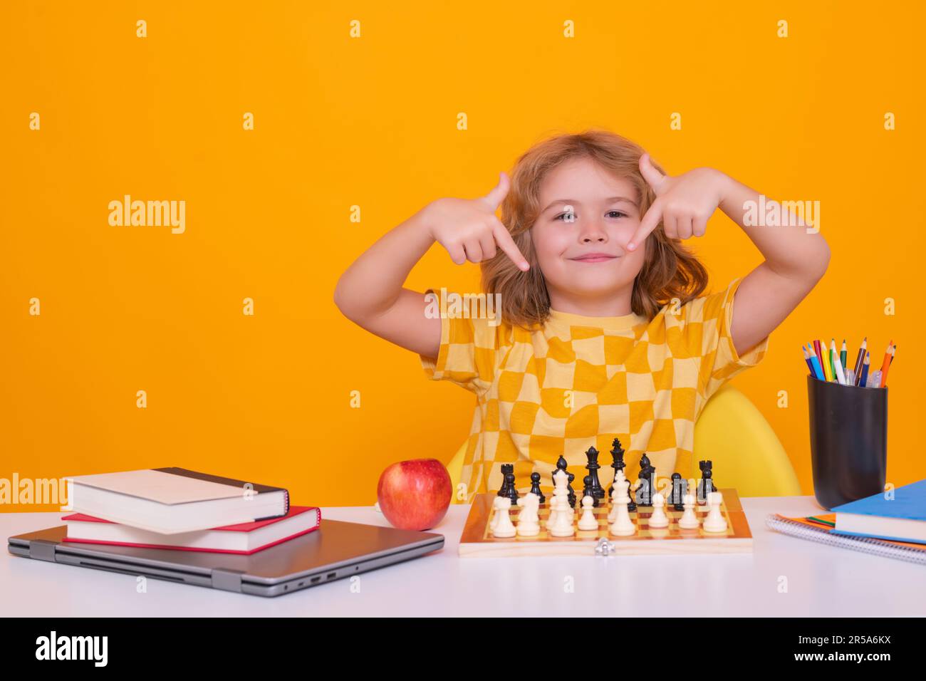 Clever child thinking about chess. Portrait of clever kid with chessboard. Boy play chess. Kid ...