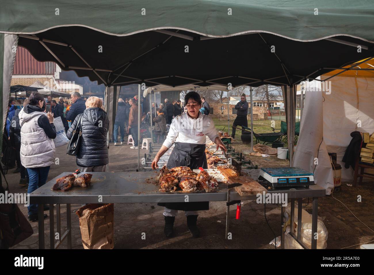 Picture of woman serving a roasting pork on display on a grill aside ...