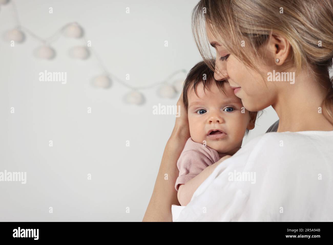 Mother hugging her cute little baby indoors, space for text Stock Photo ...