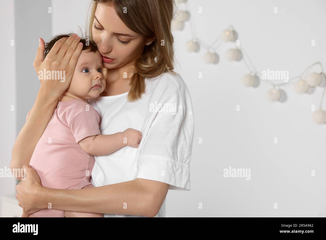 Mother hugging her cute little baby indoors, space for text Stock Photo ...