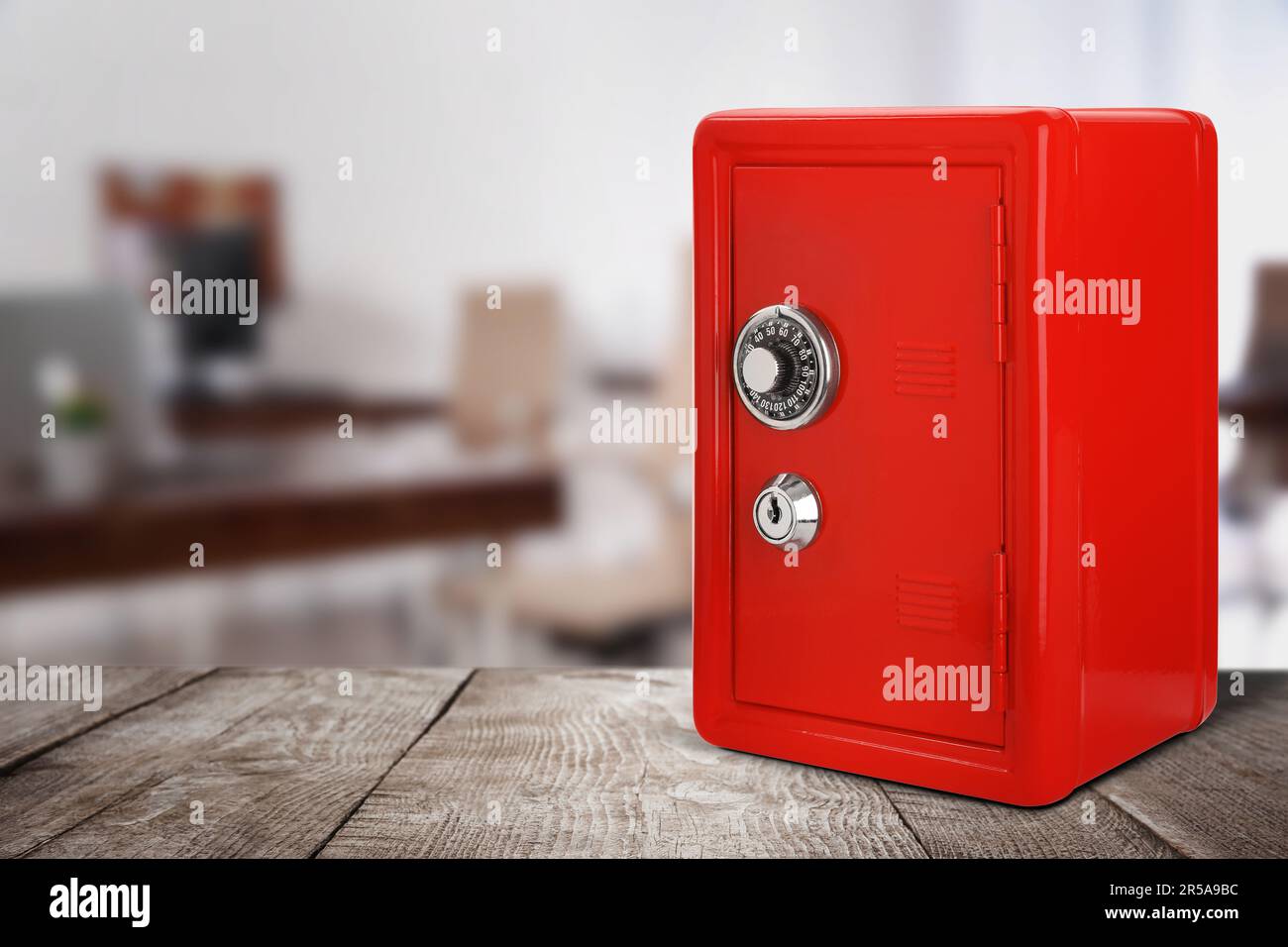 Red closed steel safe with mechanical lock on wooden table indoors ...