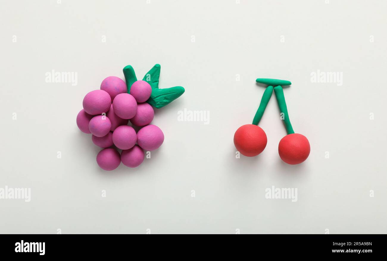 Colorful grapes and cherry made from plasticine on white background ...