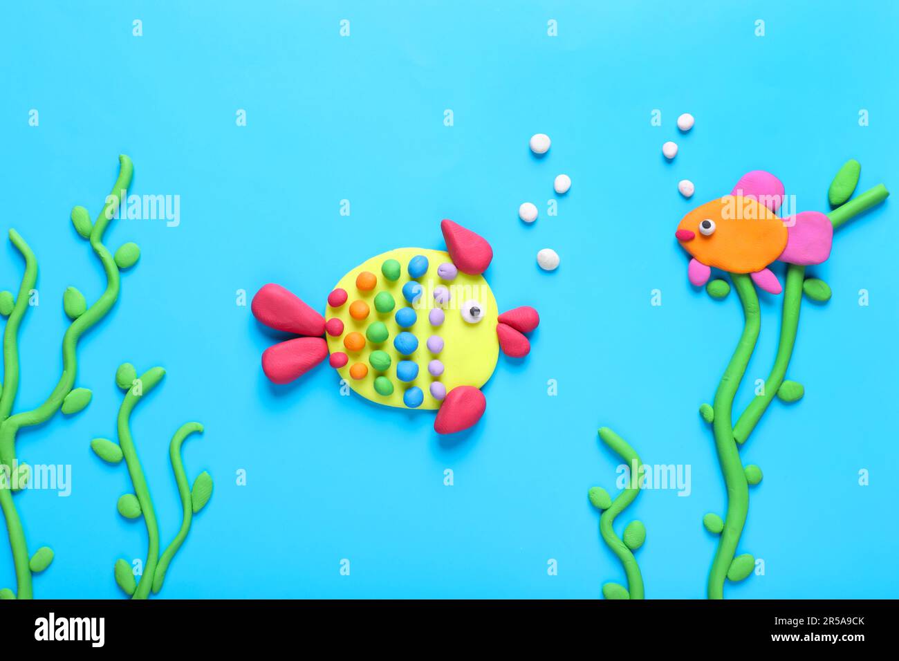 Seaweed and fish made of plasticine on light blue background, flat lay ...