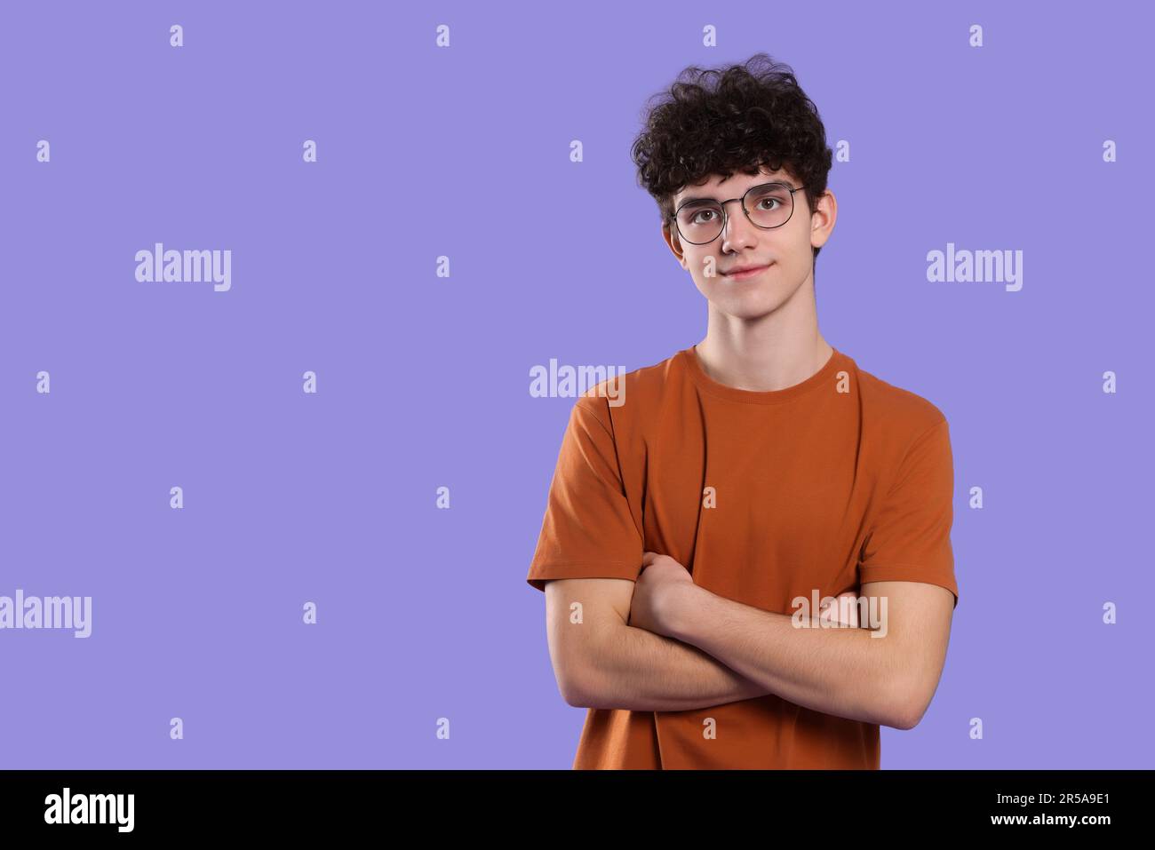 Portrait of teenage boy wearing glasses on violet background. Space for ...