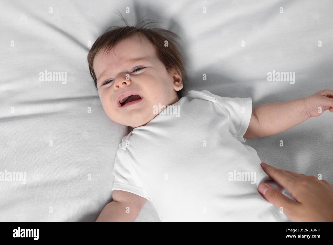 Cute little baby crying on bed, closeup Stock Photo - Alamy