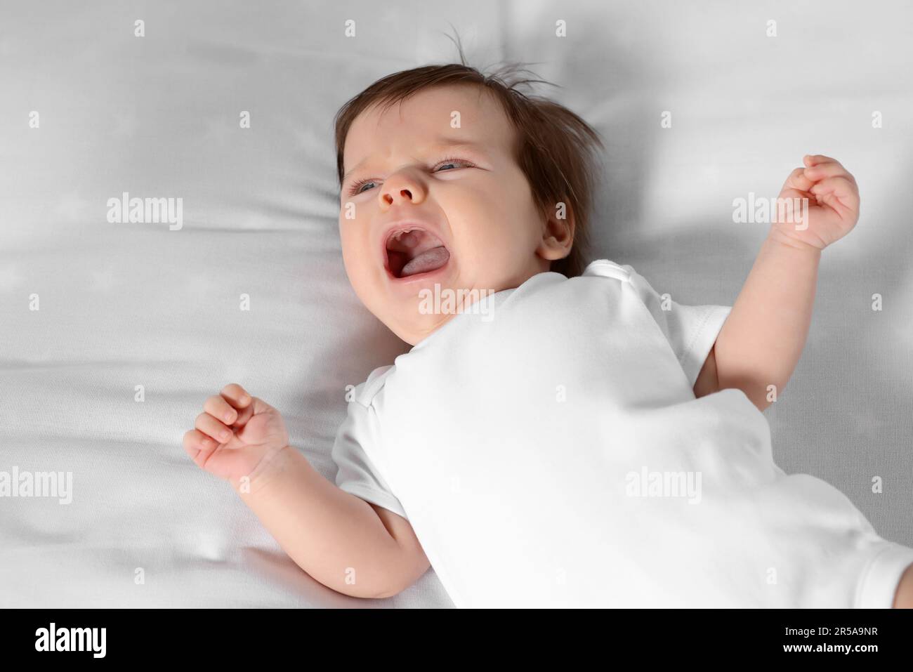 Cute little baby crying on soft bed Stock Photo - Alamy
