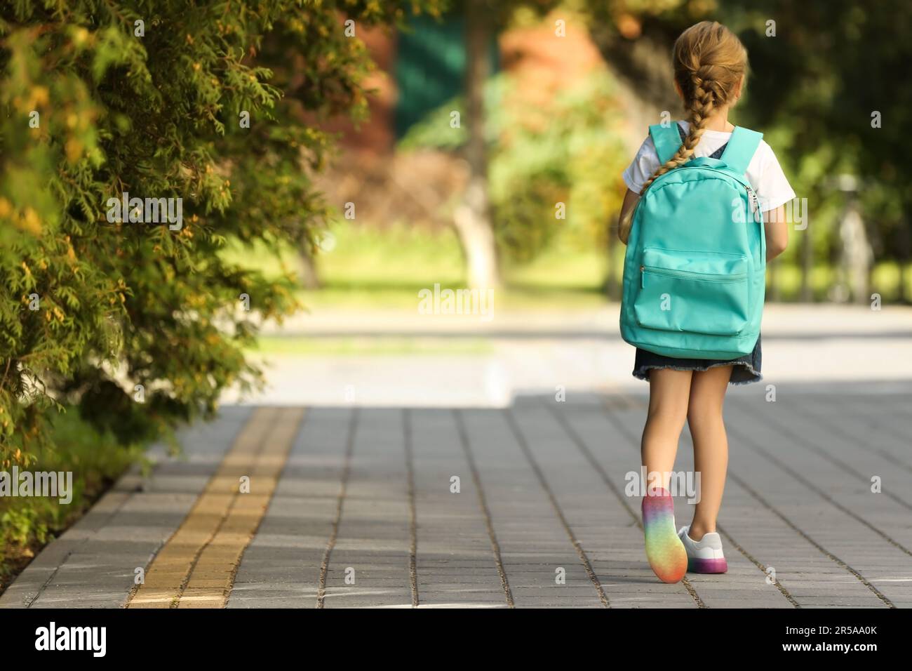 Little girl with backpack going to school, back view. Space for text ...