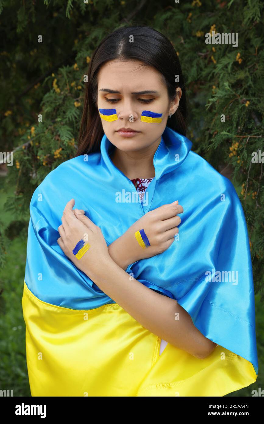 Sad young woman with Ukrainian flag outdoors Stock Photo - Alamy