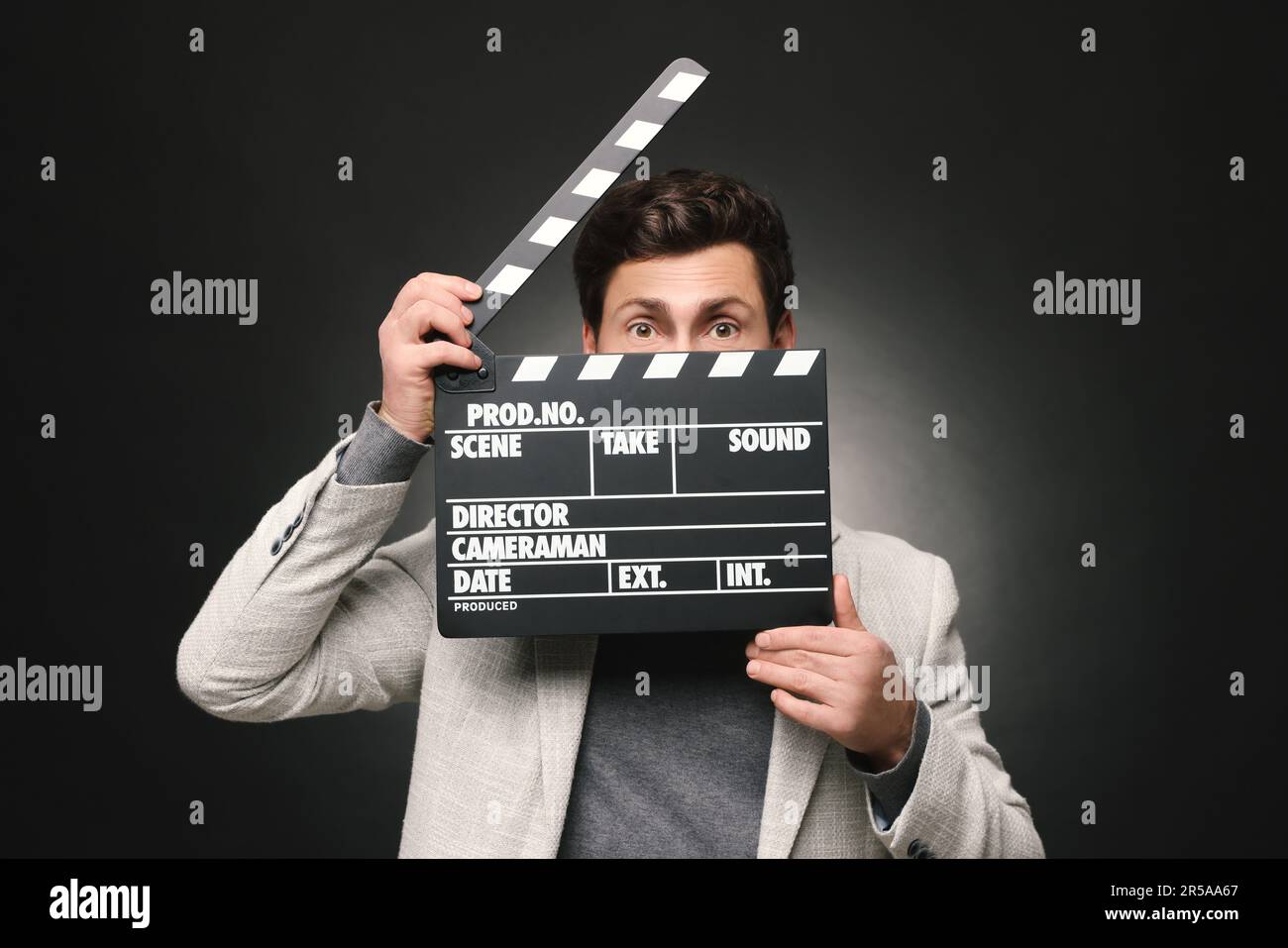 Surprised actor holding clapperboard on black background Stock Photo ...