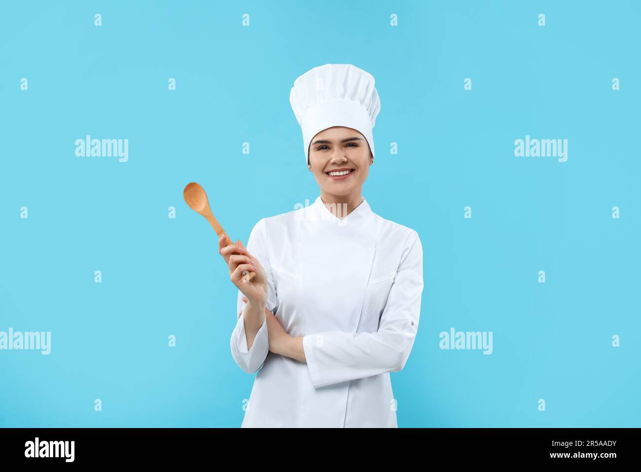 Happy chef with wooden spoon on light blue background Stock Photo - Alamy