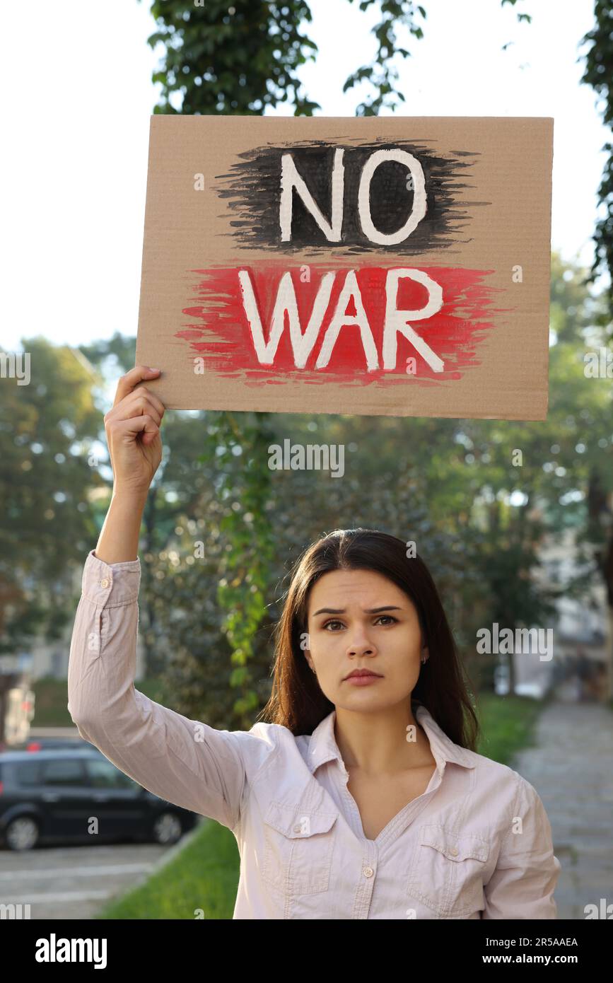 Sad woman holding poster with words No War on city street Stock Photo ...