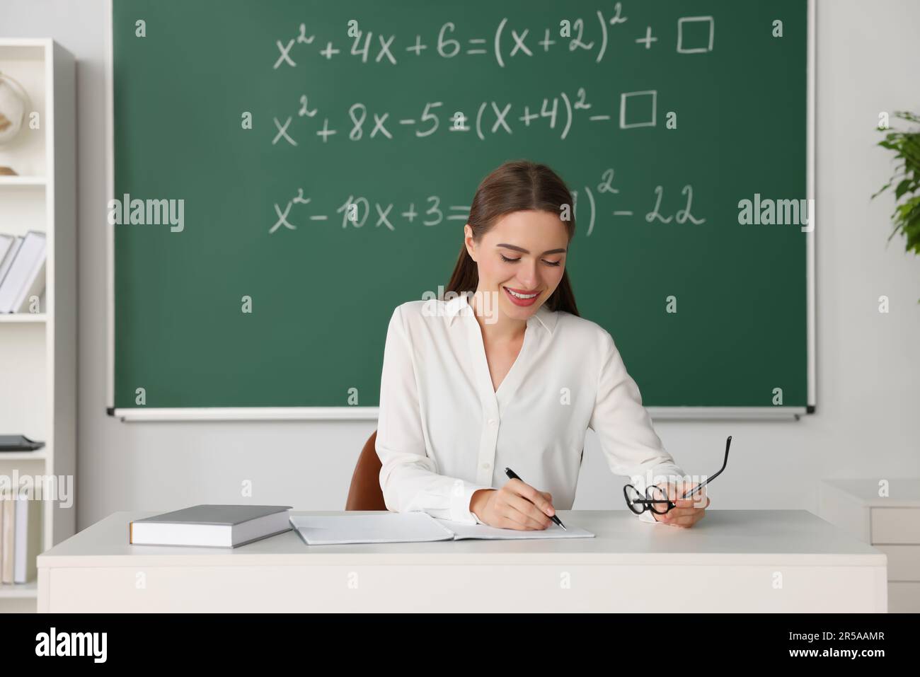 Young math’s teacher giving lesson at table in classroom Stock Photo ...