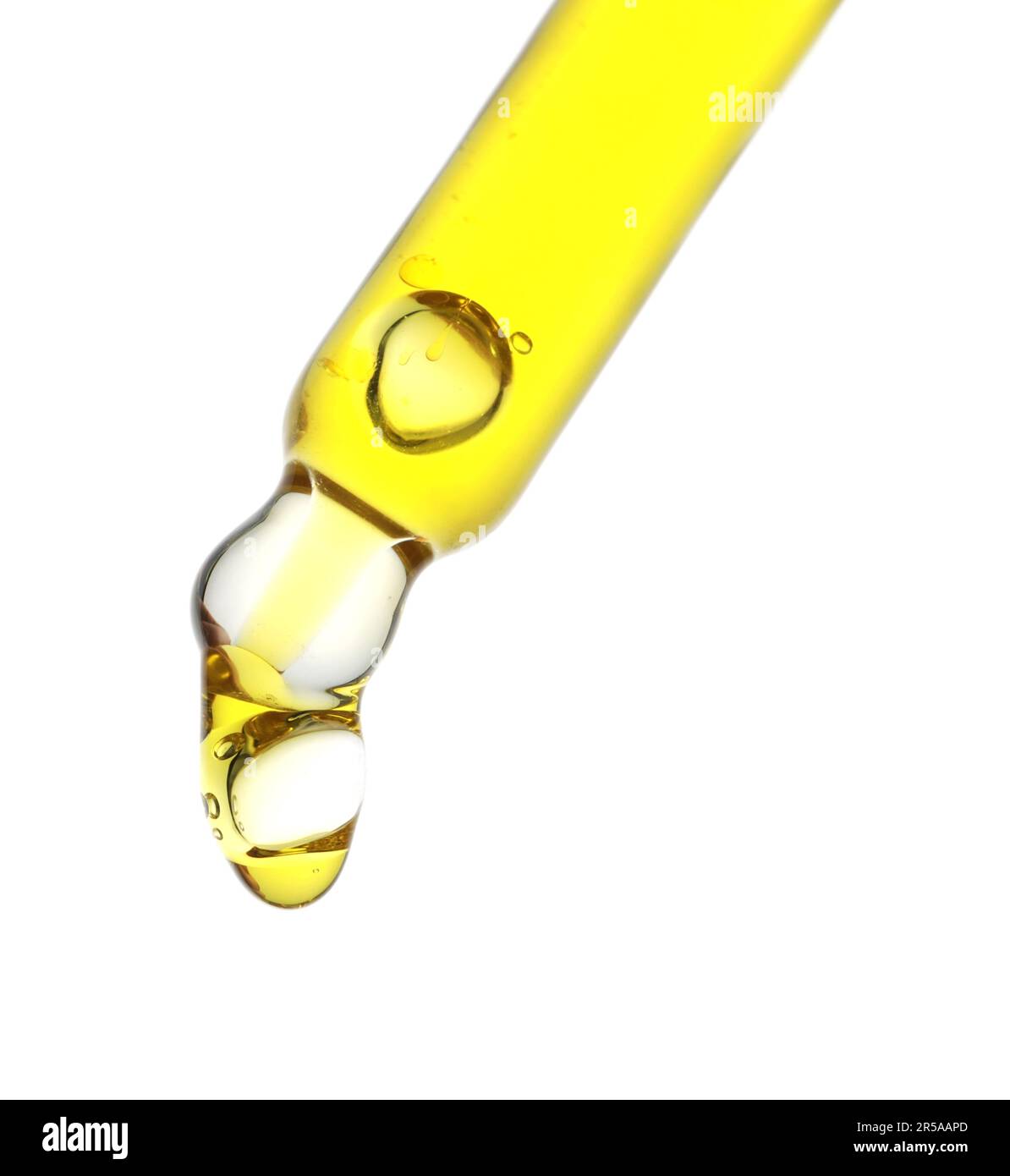 Dripping yellow facial serum from pipette on white background, closeup ...