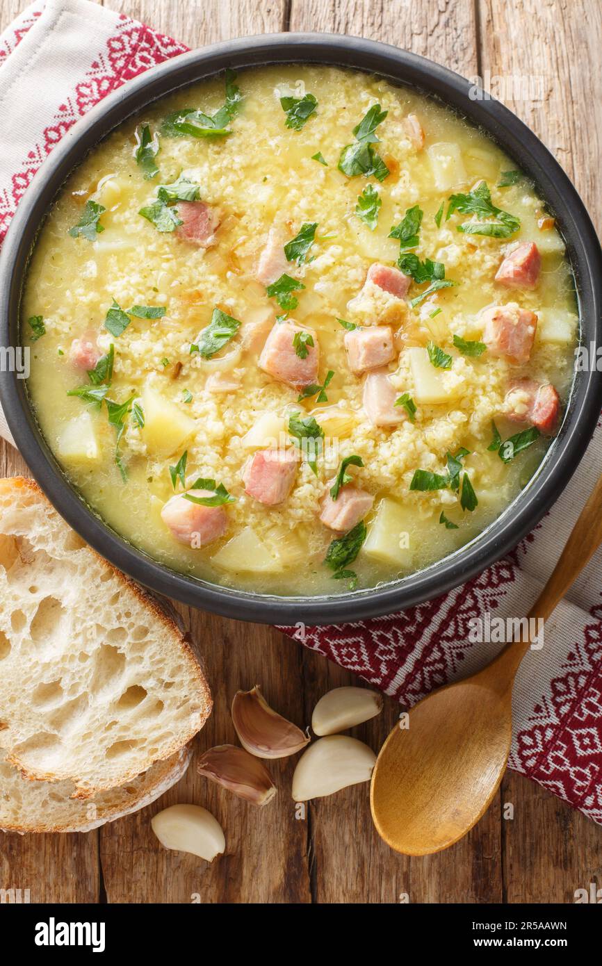 Soup kulesh with millet, potatoes and bacon in a black bowl on a wooden ...