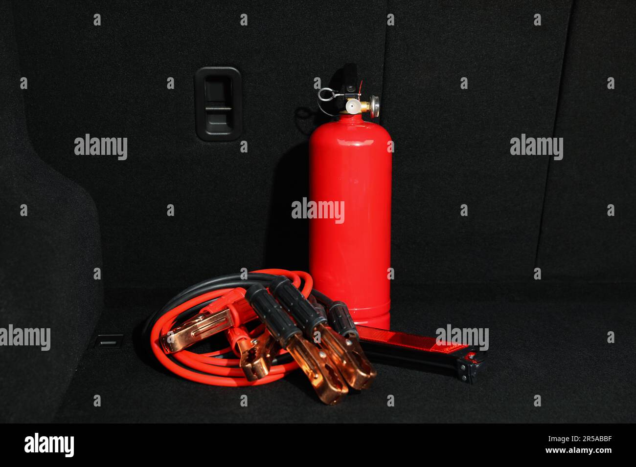 Red fire extinguisher and battery jumper cables in trunk. Car safety ...