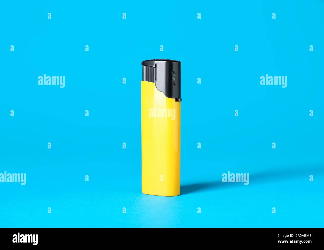 Yellow plastic cigarette lighter on light blue background Stock Photo ...