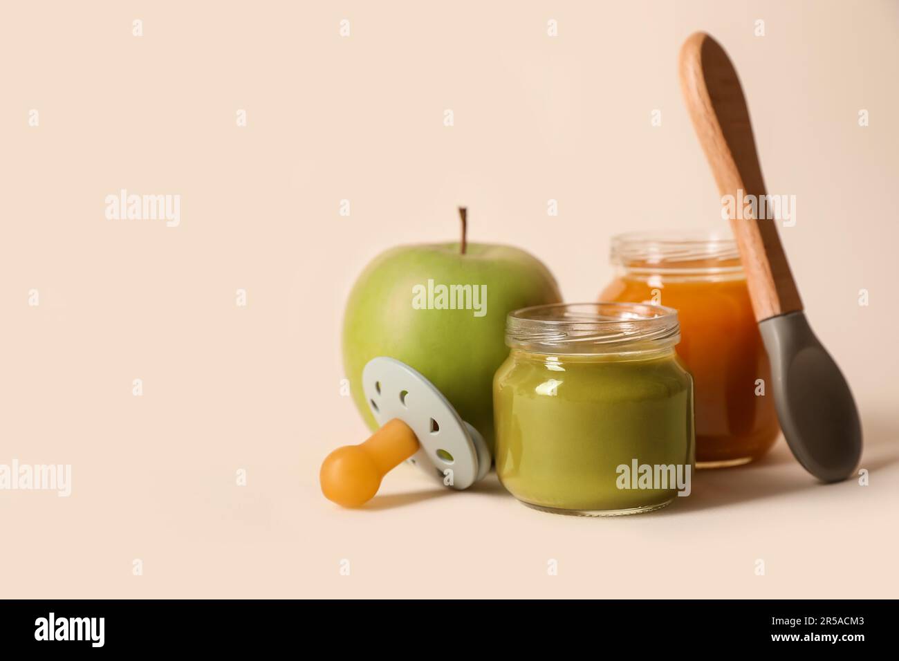 Healthy baby food, apple, pacifier and spoon on beige background. Space ...